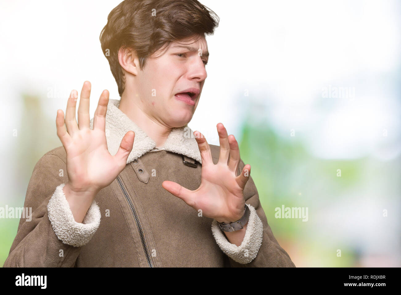 Young handsome man wearing winter coat over isolated background afraid ...
