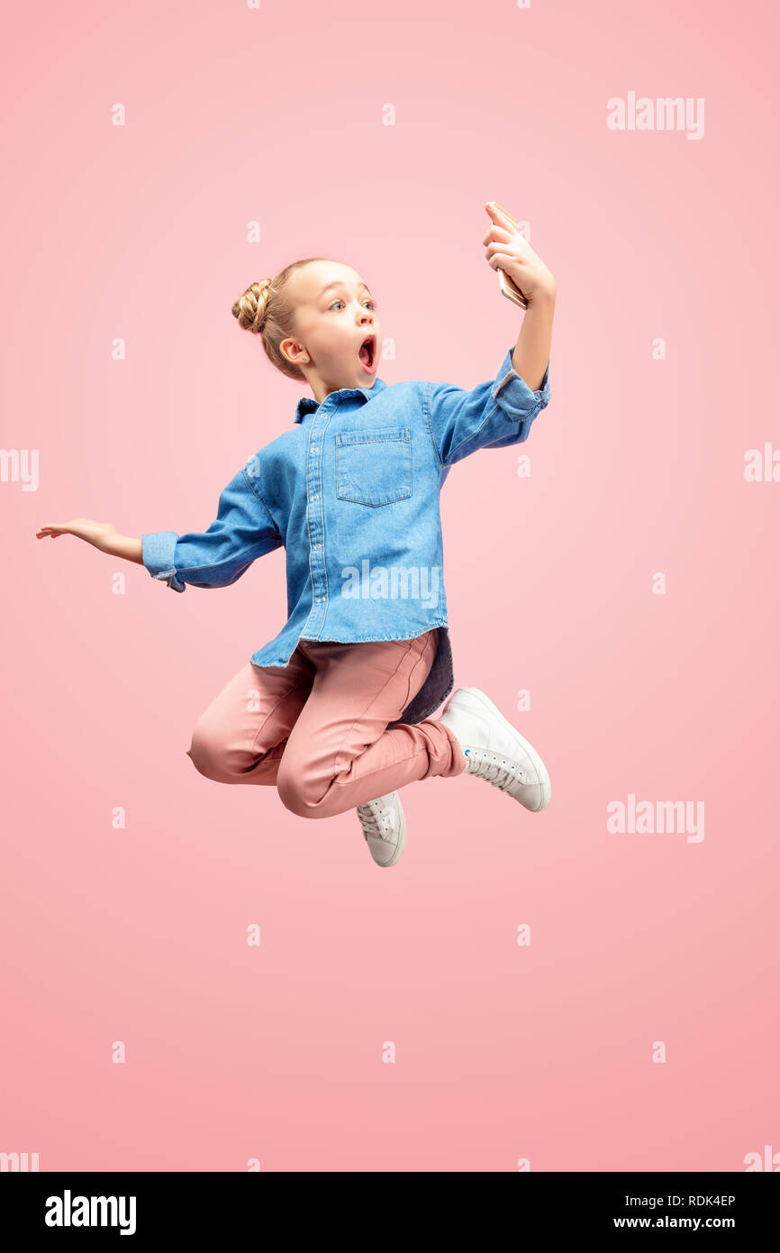 Young happy surprised caucasian teen girl jumping with mobile phone in ...