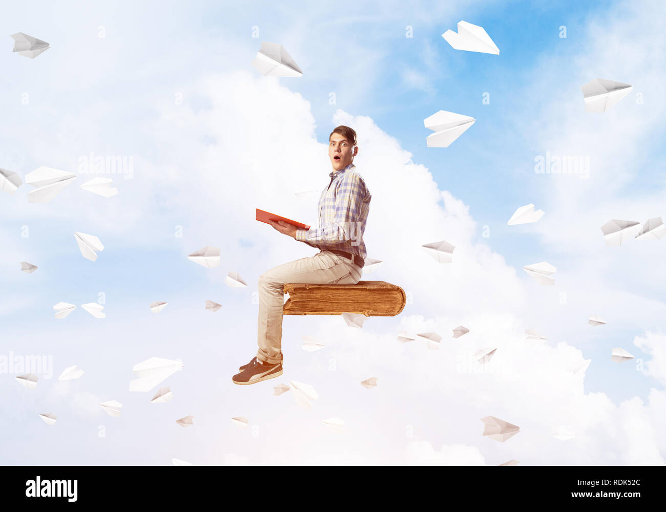 Handsome man student reading book and paper planes flying around Stock ...
