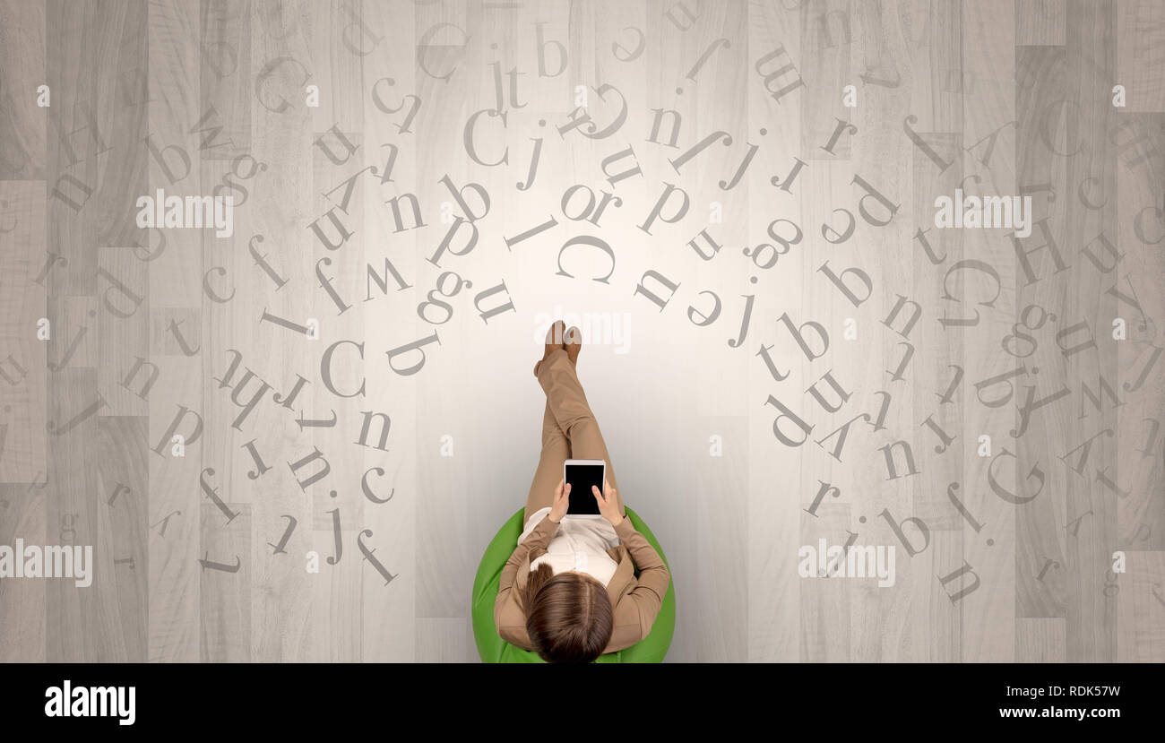 Letters with writer using tablet in a beige chair and an office space ...