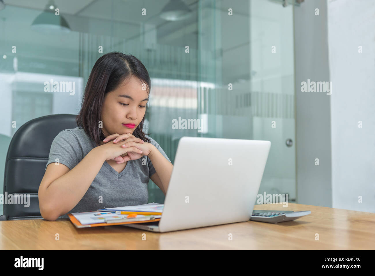 Female manager reading financial report and working on laptop Stock ...