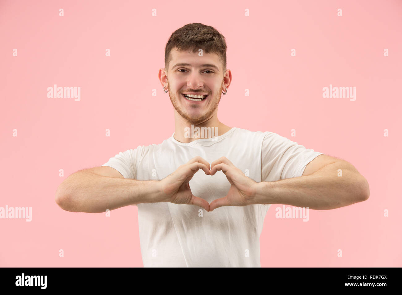 Attractive guy is making a heart shape symbol with his fingers. He is ...