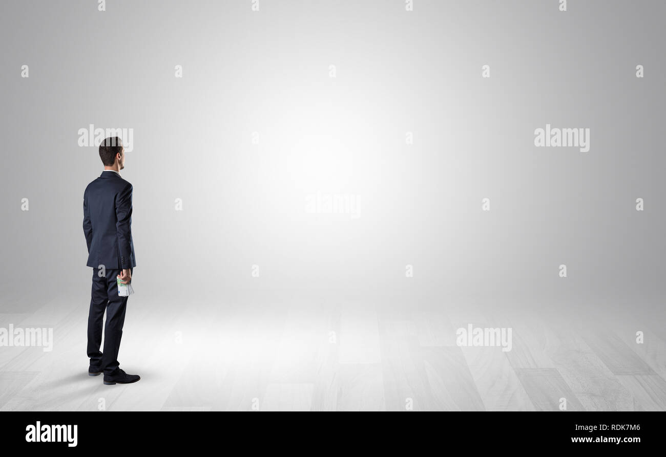 Man standing with his back in an empty room with object in his hand ...