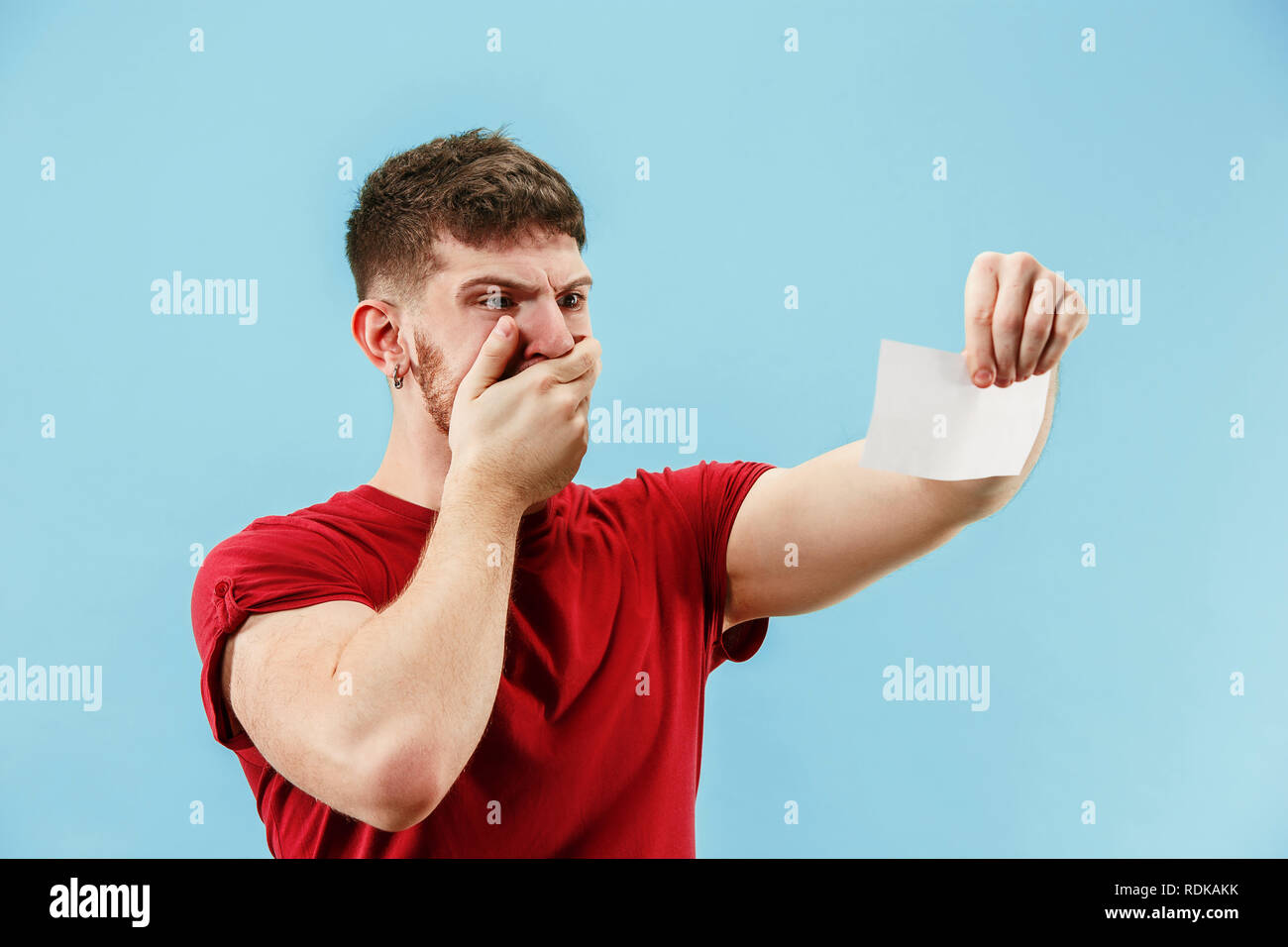 Young boy with a surprised unhappy failure expression bet slip on blue ...