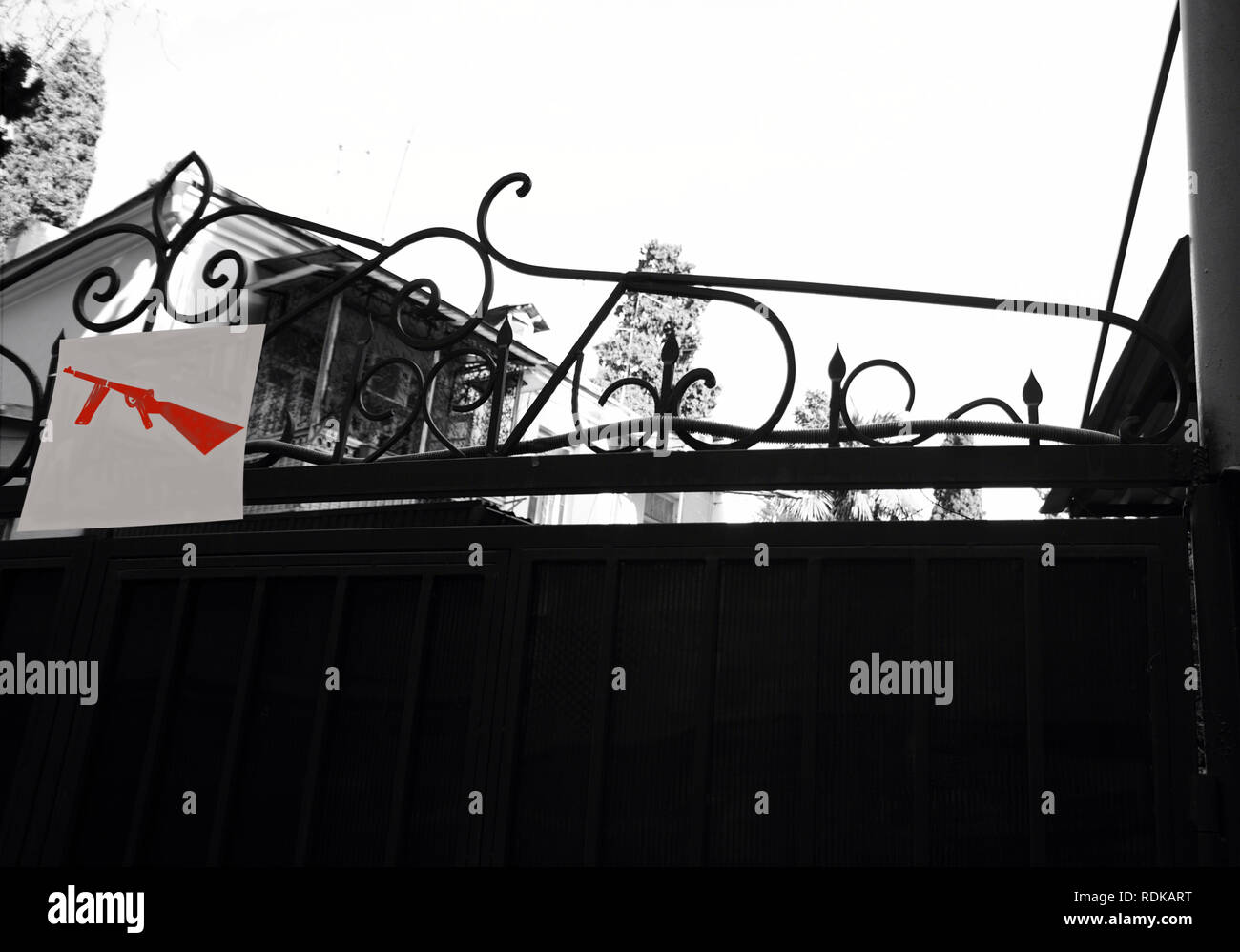 Locked metal gate with a gun drawn on the warning sign, concept of ...