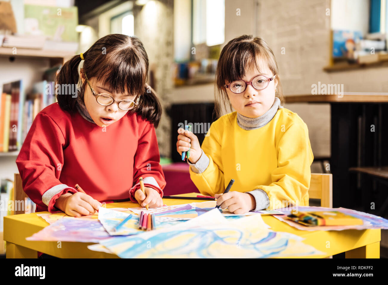 Two girls with congenital acromicria wearing glasses drawing together ...