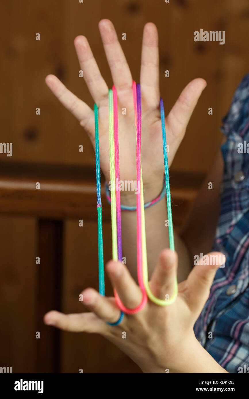 Child playing classic, old-school string game and didactic toy with her ...