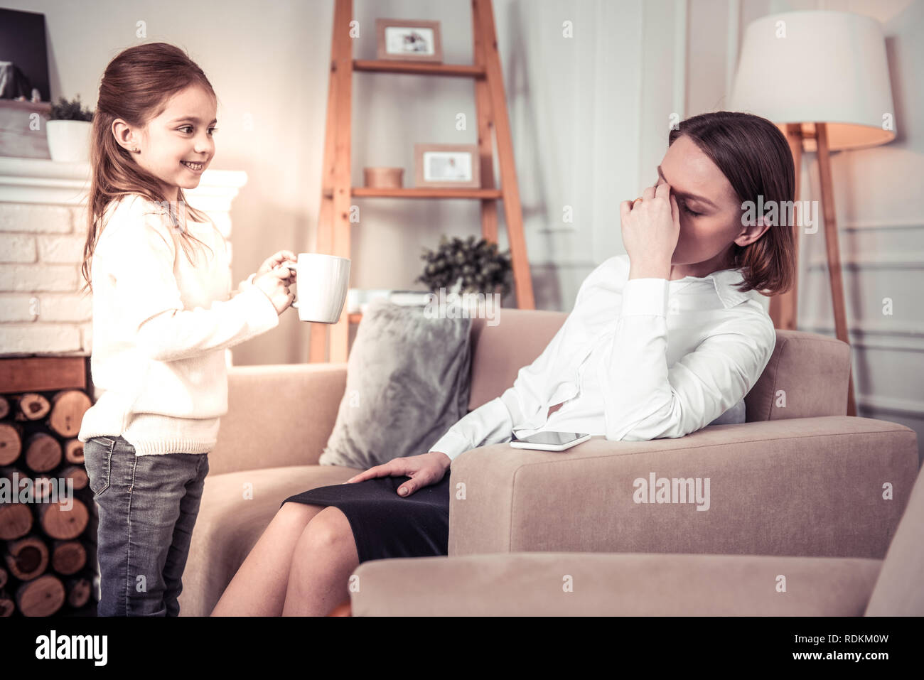 Joyful nice girl bringing tea to her mother Stock Photo - Alamy