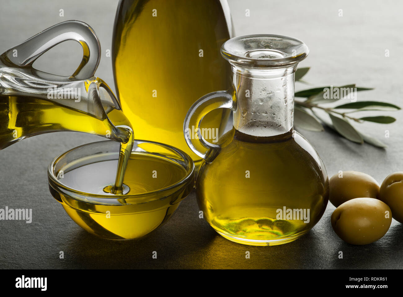 Organic olive oil. Bottle of Extra virgin oil pouring in to glass bowl ...