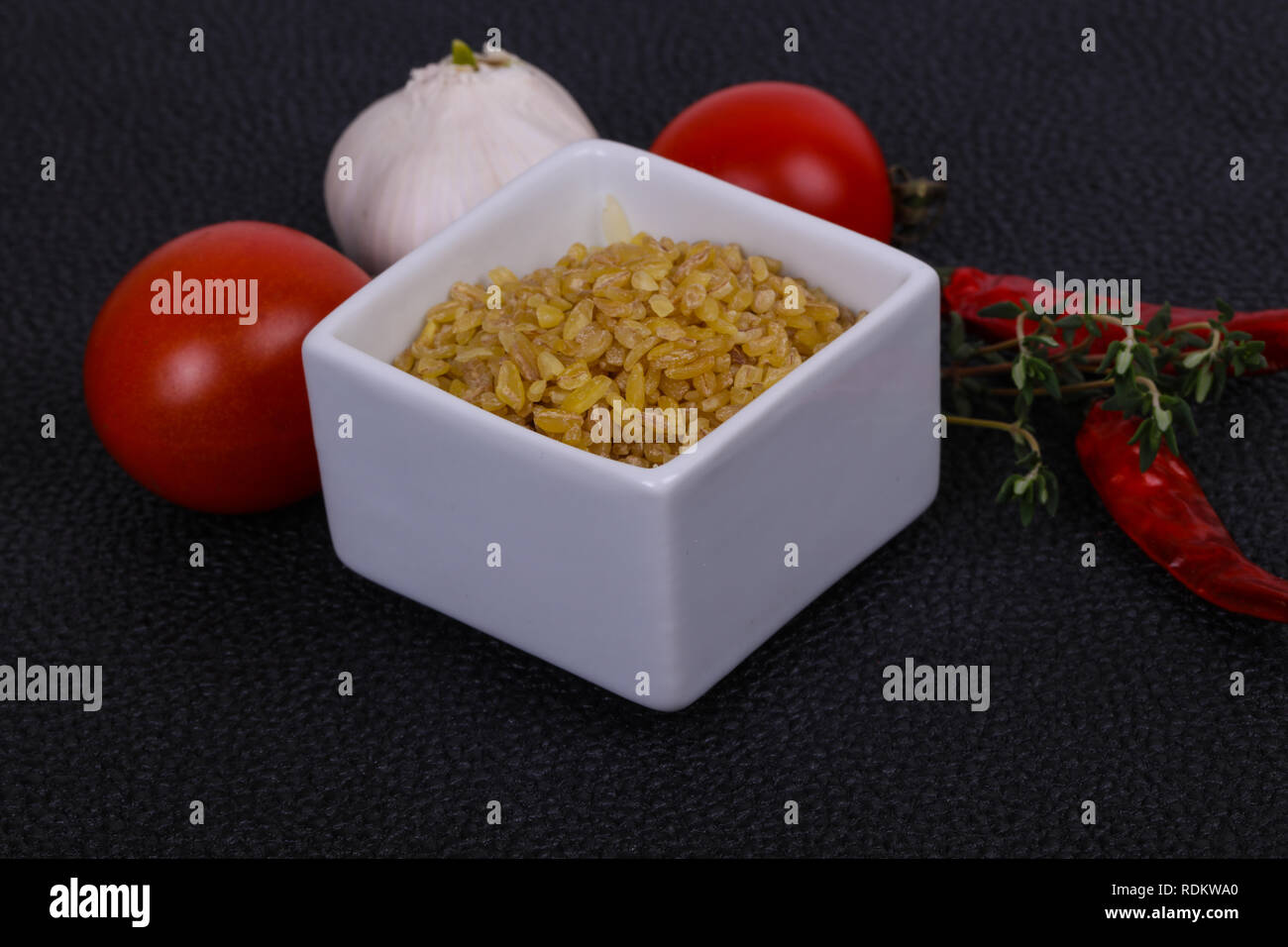Raw golden bulgur in the bowl with tomatoes and garlic Stock Photo - Alamy
