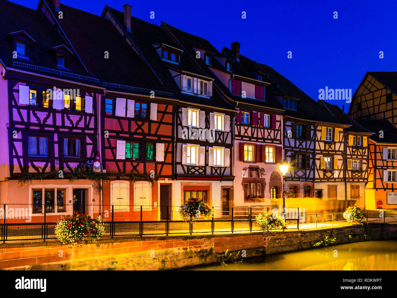 Old colorful houses illuminated, small river, water reflection at night ...