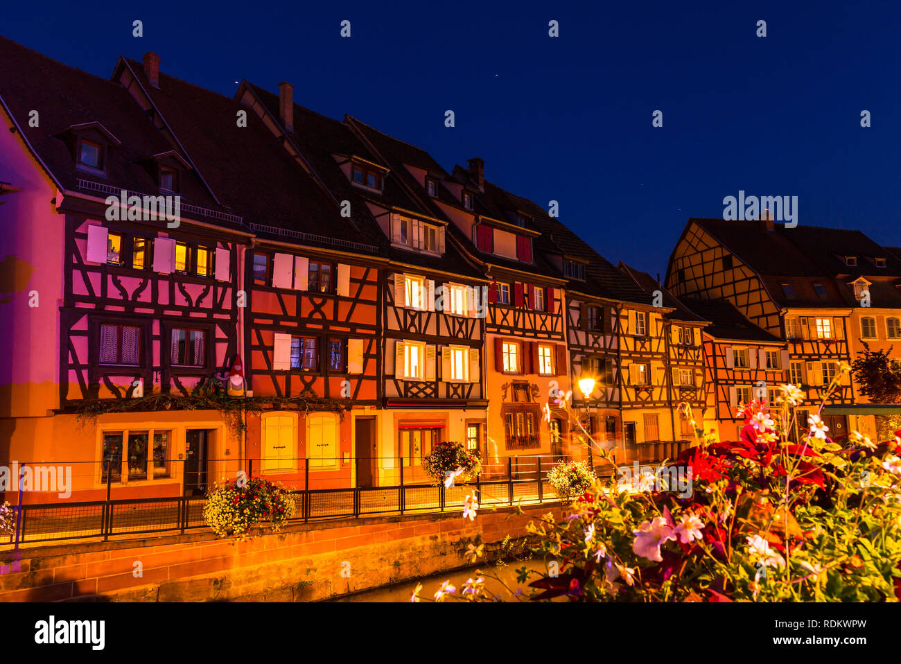 Old colorful houses illuminated, small river, water reflection at night ...