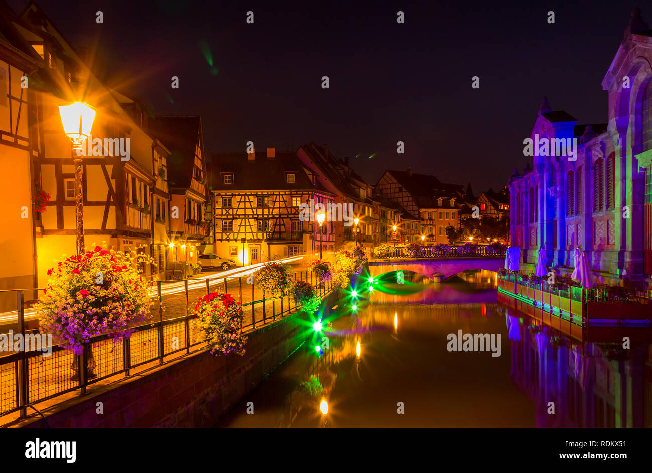 Old colorful houses illuminated, small river, water reflection at night ...