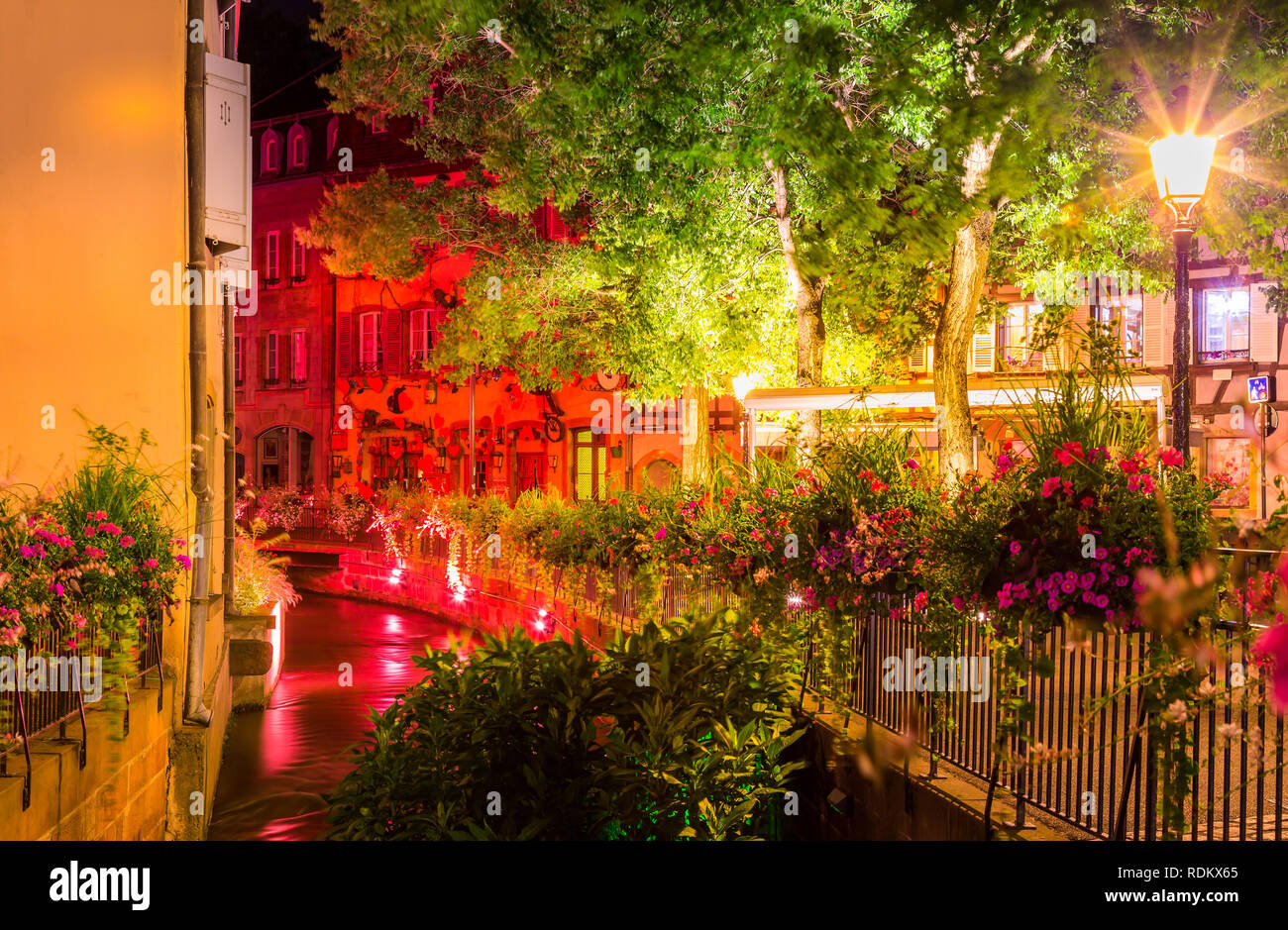 Old colorful houses illuminated, small river, water reflection at night ...