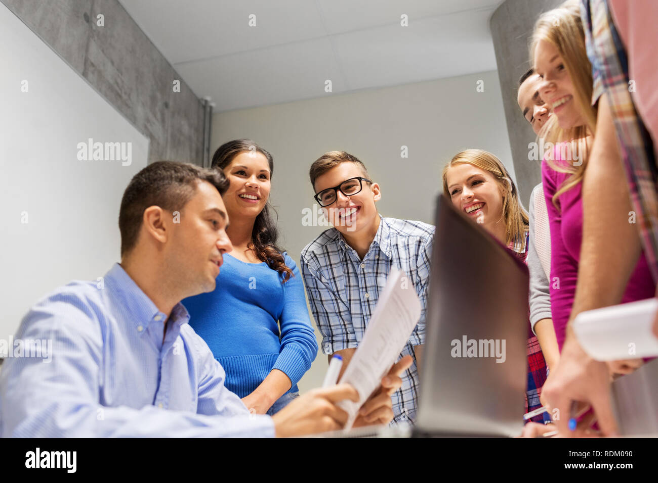 students and teacher with papers and laptop Stock Photo - Alamy