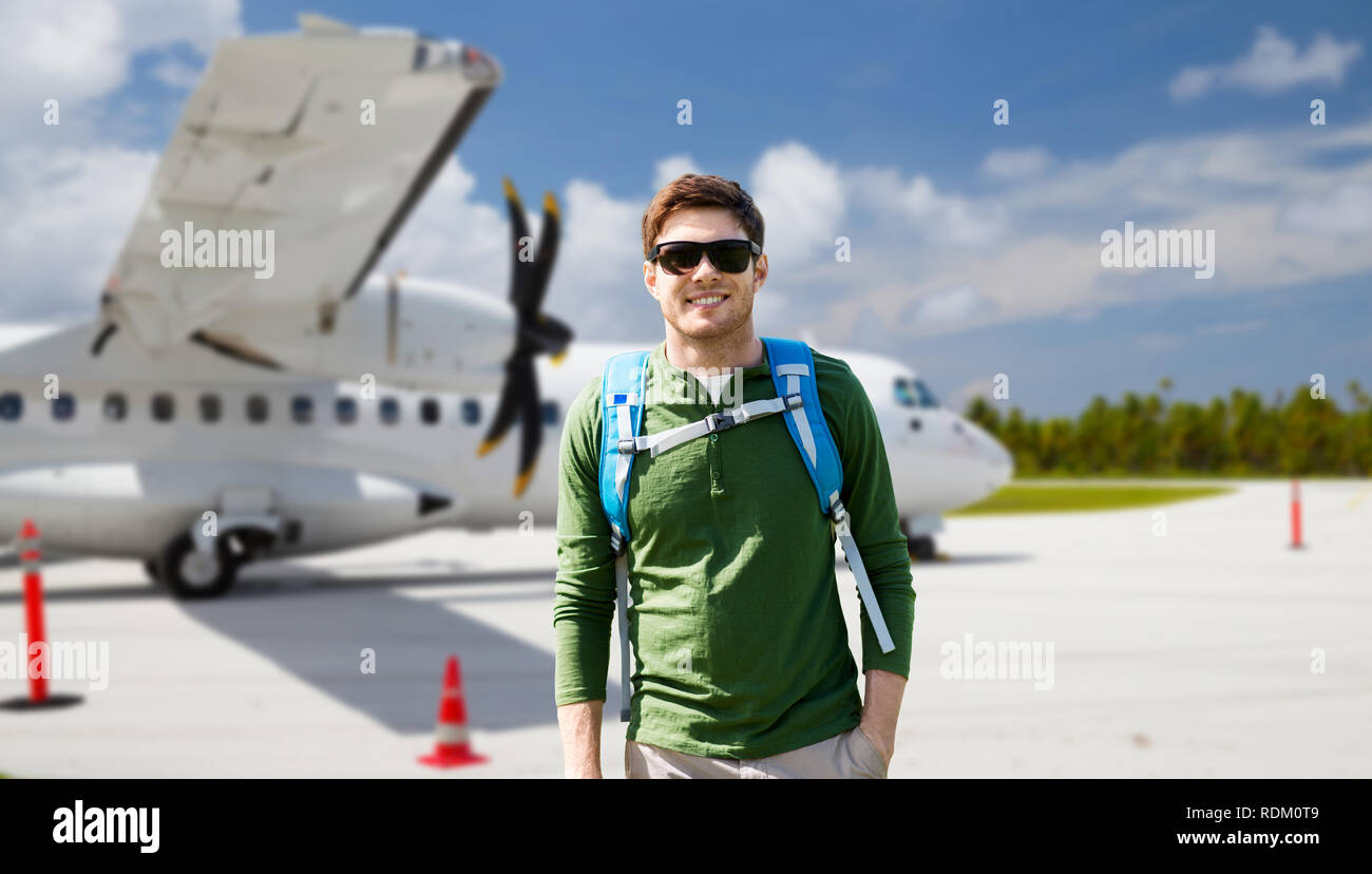 smiling man with backpack over plane on airfield Stock Photo - Alamy