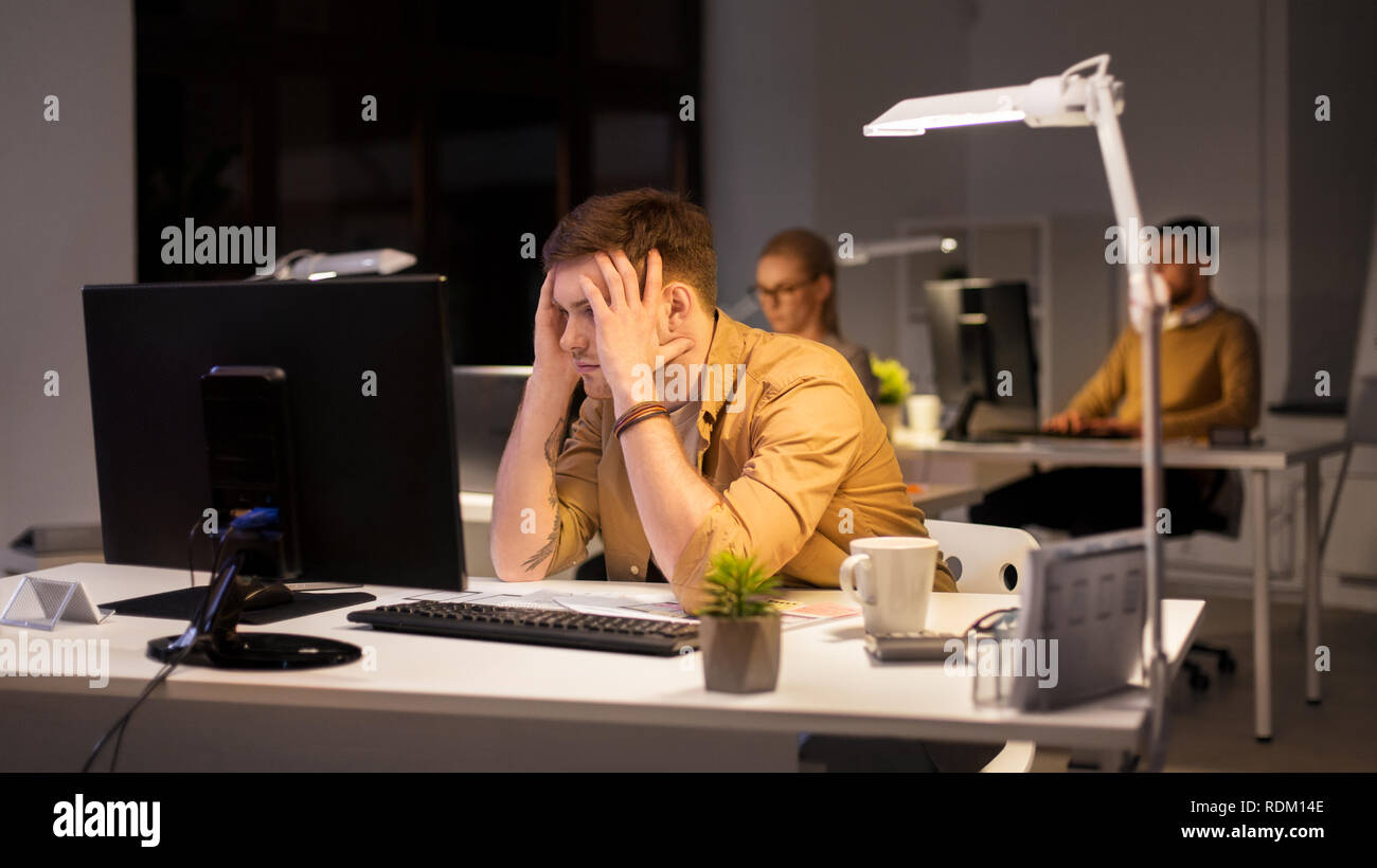 stressed man at computer monitor at night office Stock Photo - Alamy
