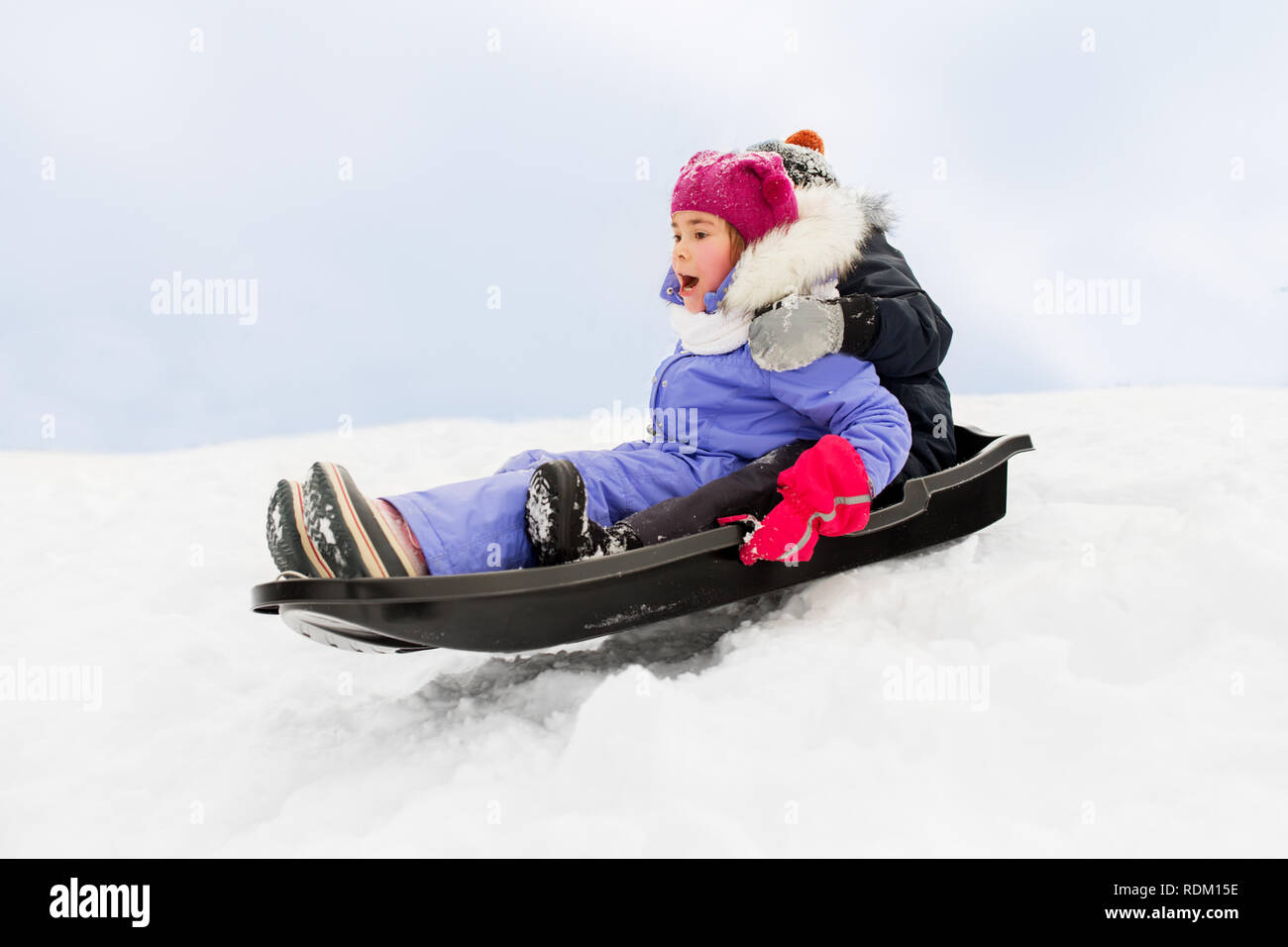 little kids sliding on sled down hill in winter Stock Photo - Alamy