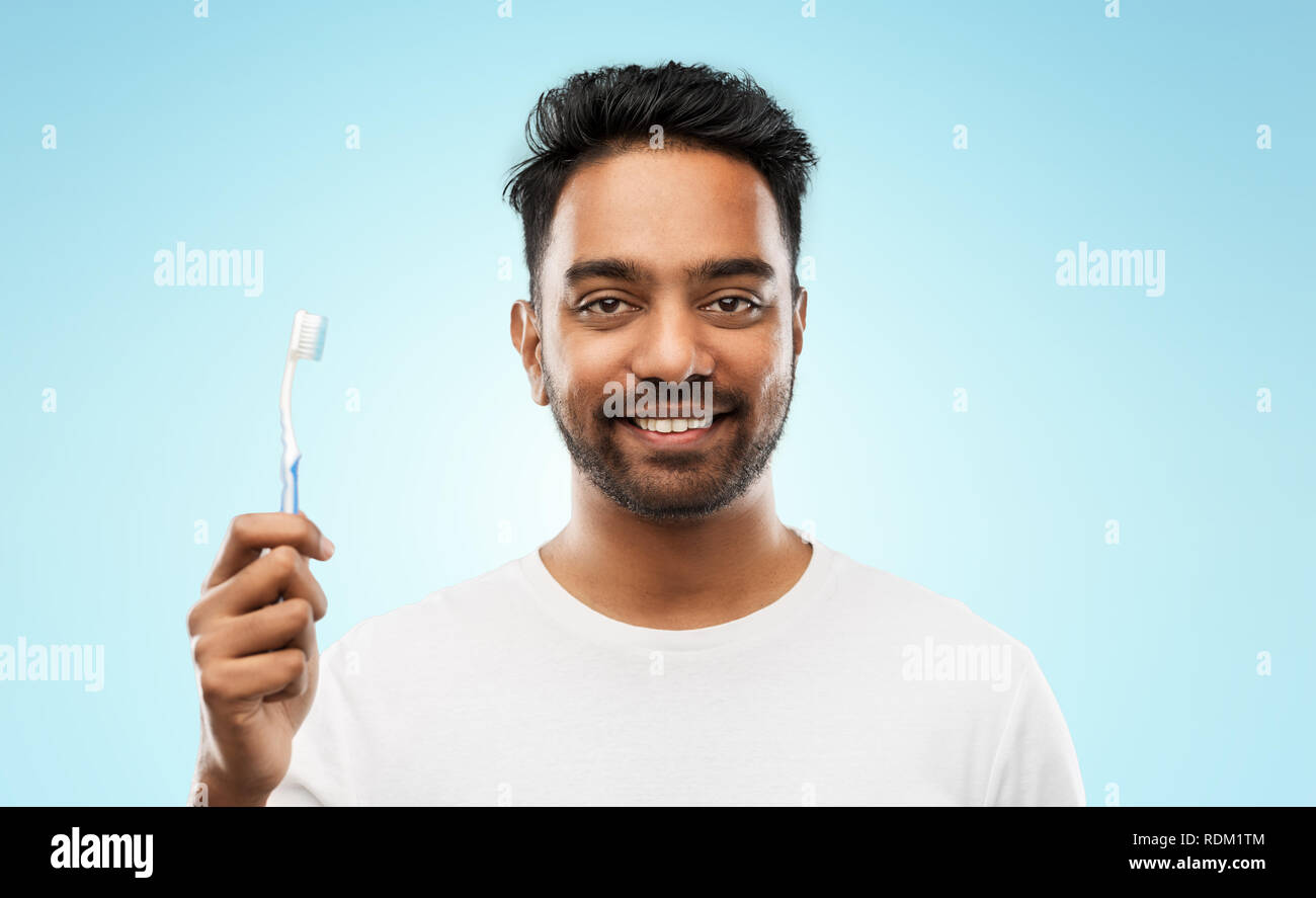indian man with toothbrush over blue background Stock Photo - Alamy