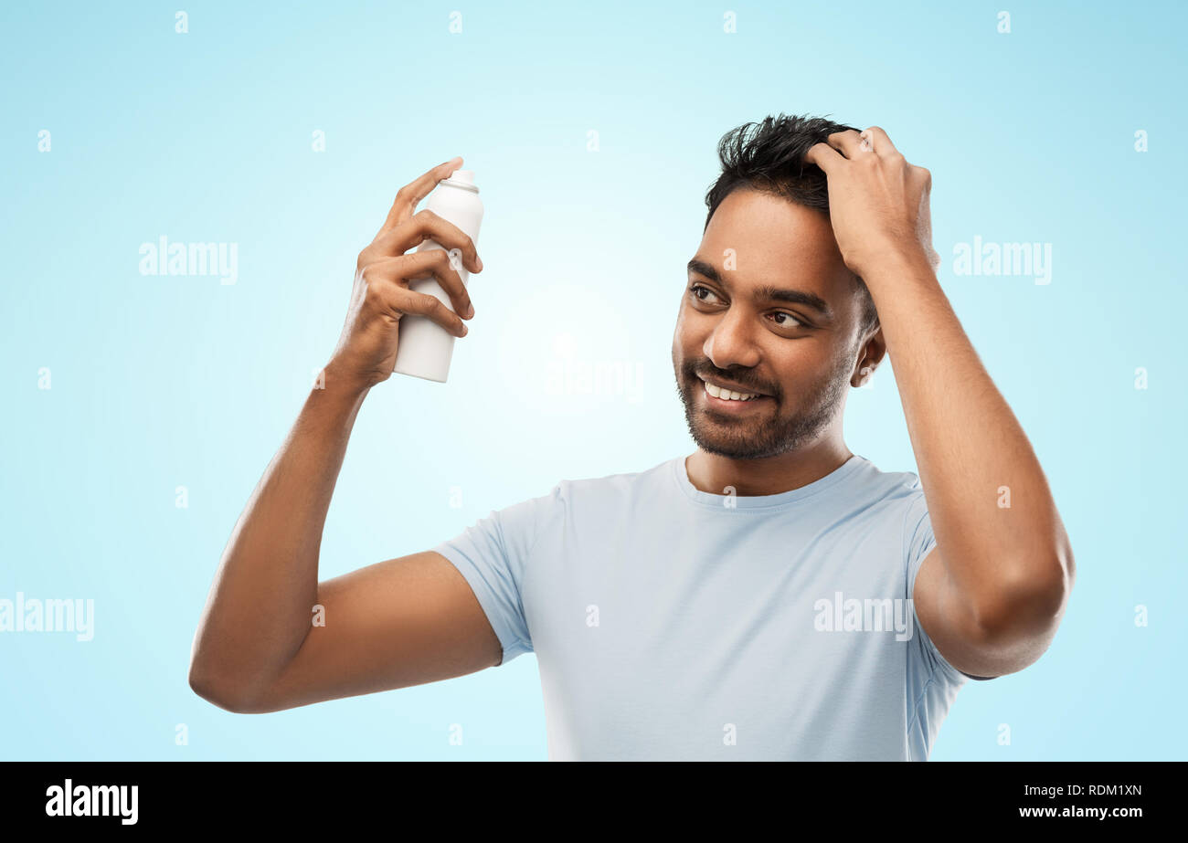 smiling indian man applying hair spray over gray Stock Photo - Alamy
