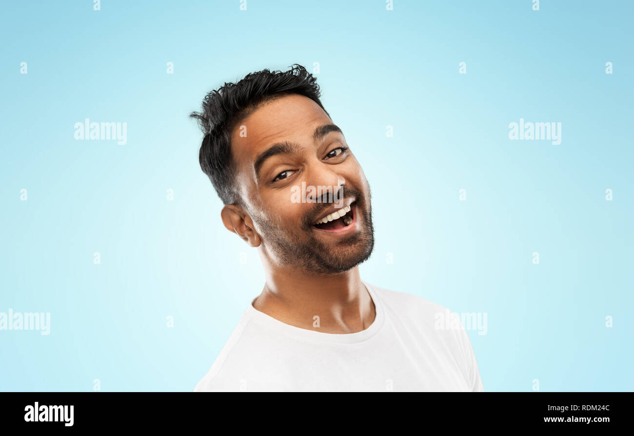 young laughing indian man over blue background Stock Photo - Alamy