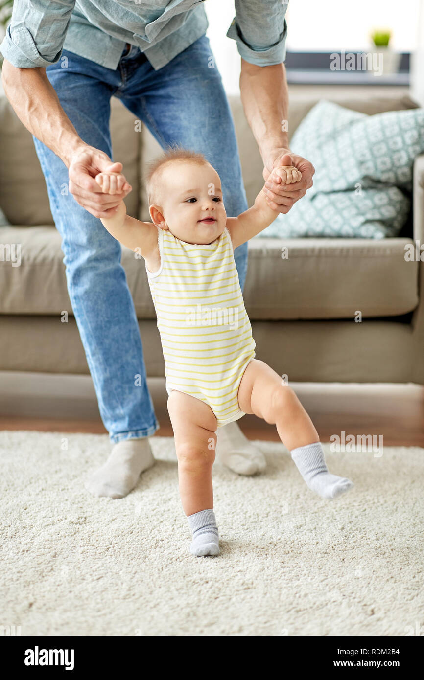 father helping baby daughter with walking at home Stock Photo - Alamy