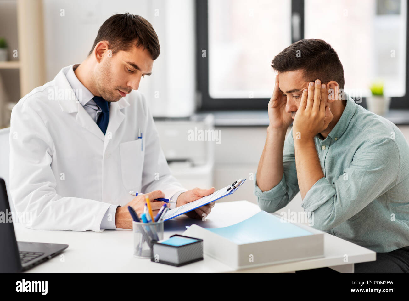Doctor taking notes hispanic patient hi-res stock photography and ...