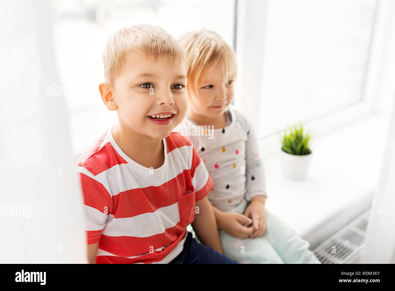 happy little kids sitting on window sill Stock Photo - Alamy