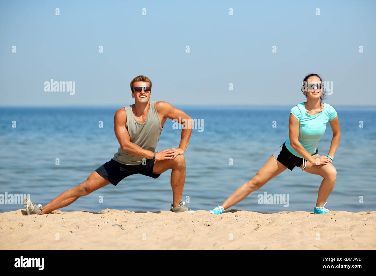 smiling couple stretching legs on beach Stock Photo - Alamy