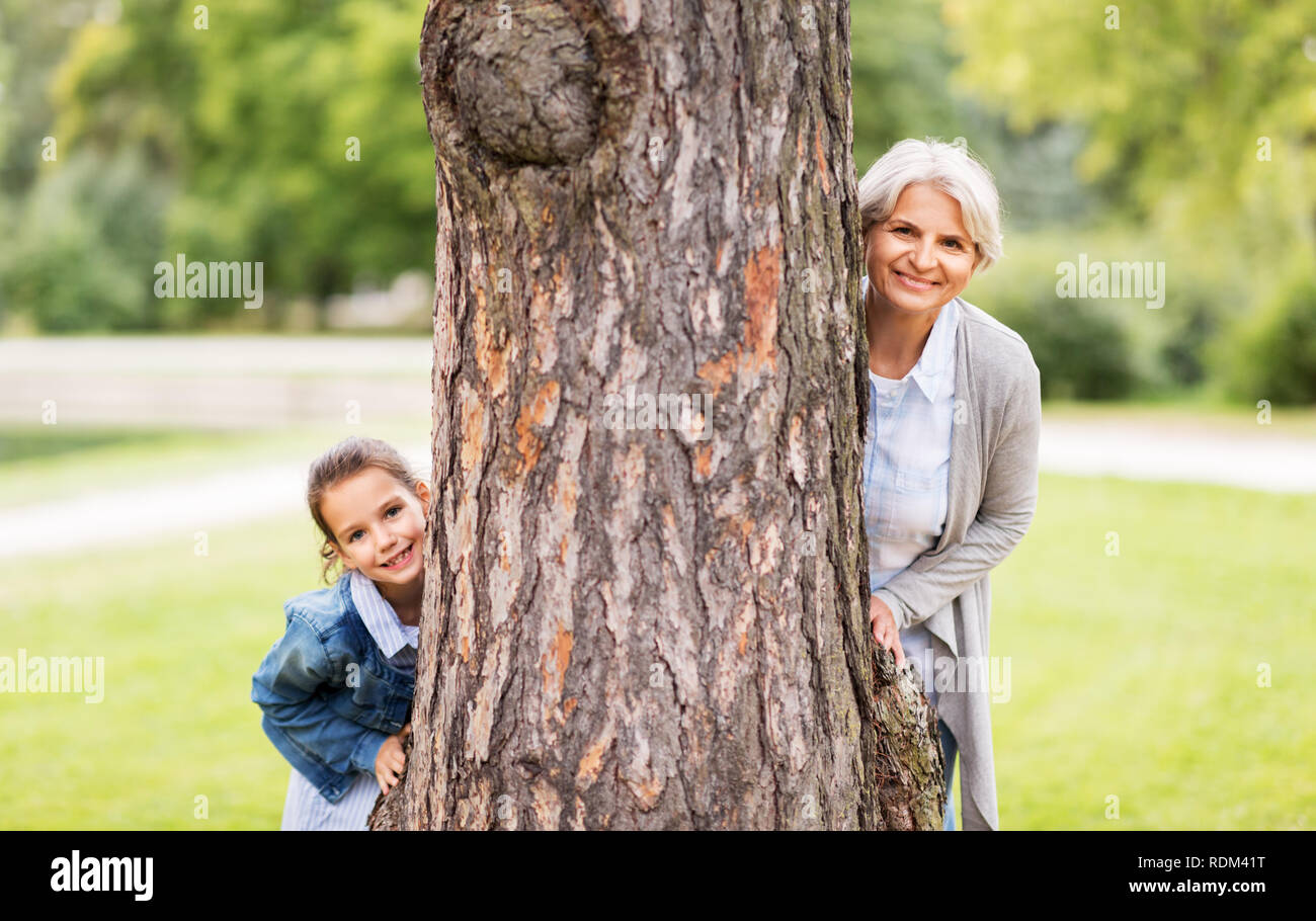 grandmother and granddaughter behind tree at park Stock Photo - Alamy