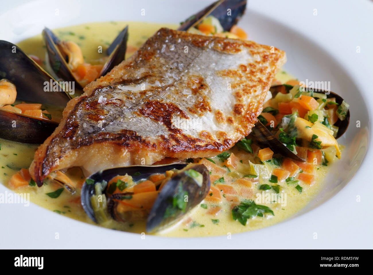 Hake fillet with mussels and saffron Stock Photo - Alamy