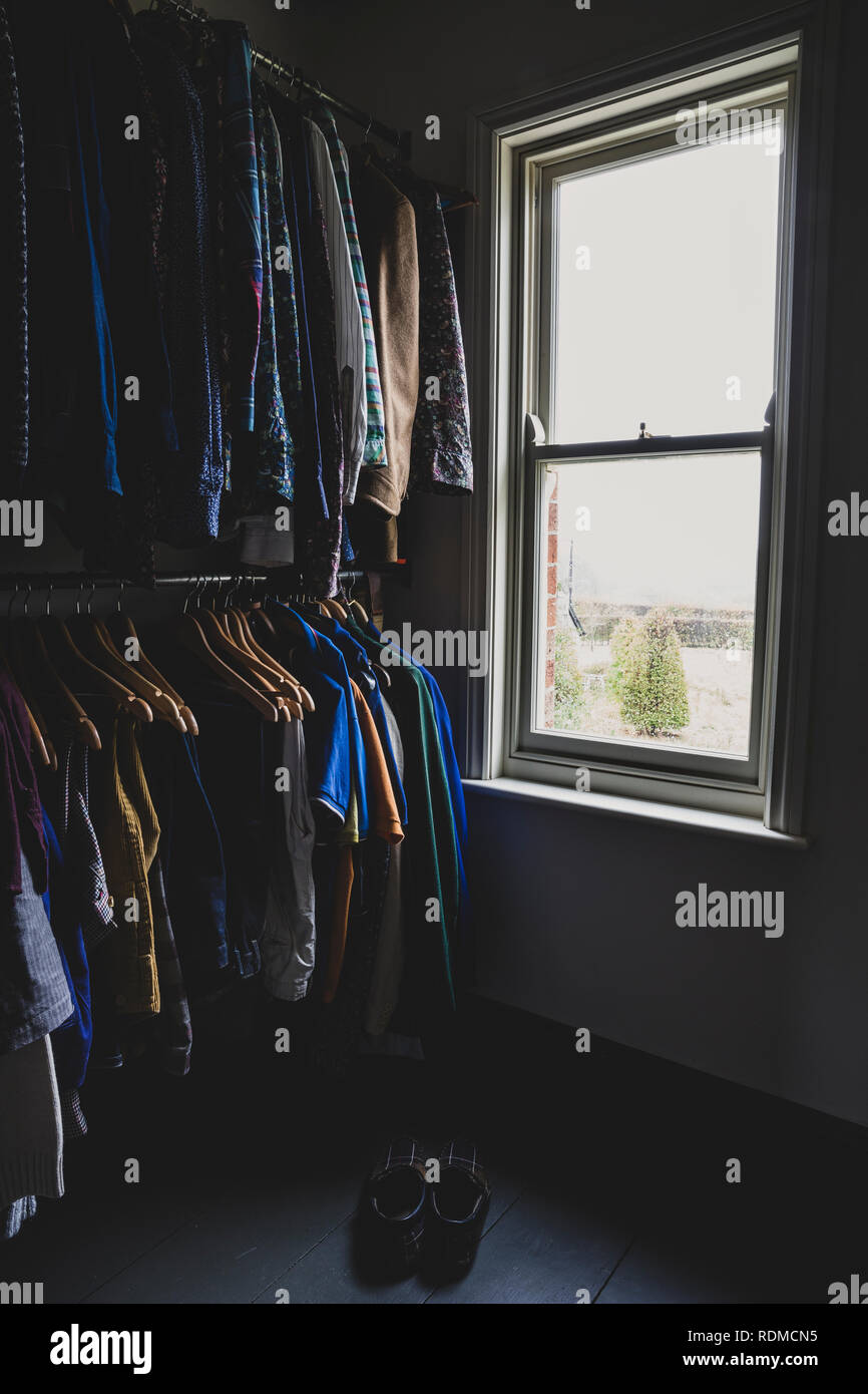 Interior view of walk-in wardrobe with sash window and clothing on ...
