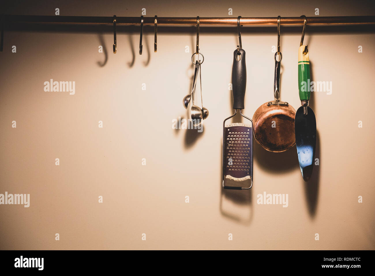 Close up of kitchen utensils suspended from copper pipe Stock Photo - Alamy