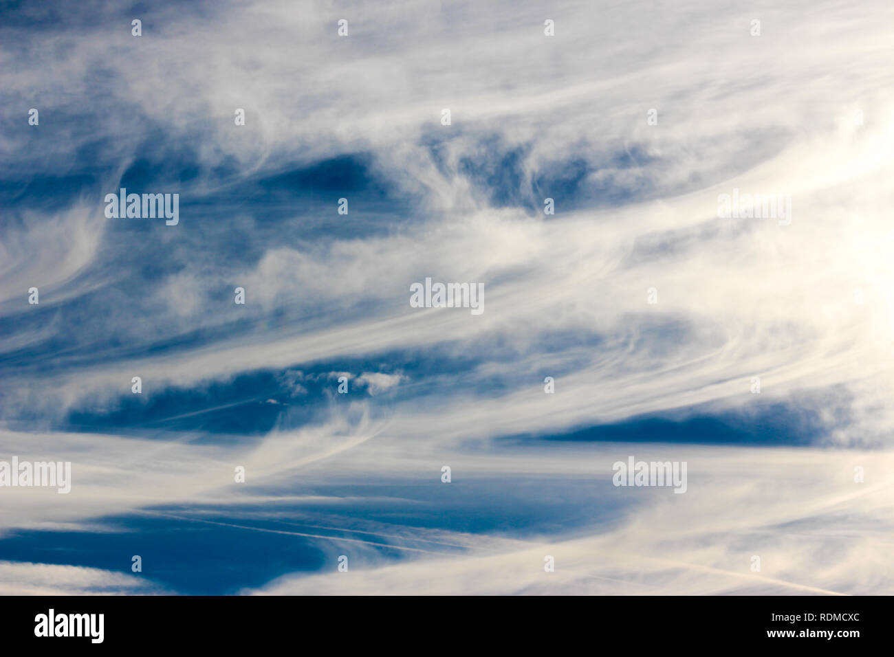 Multiple contrails cross paths through the sky above a layer of cloud ...