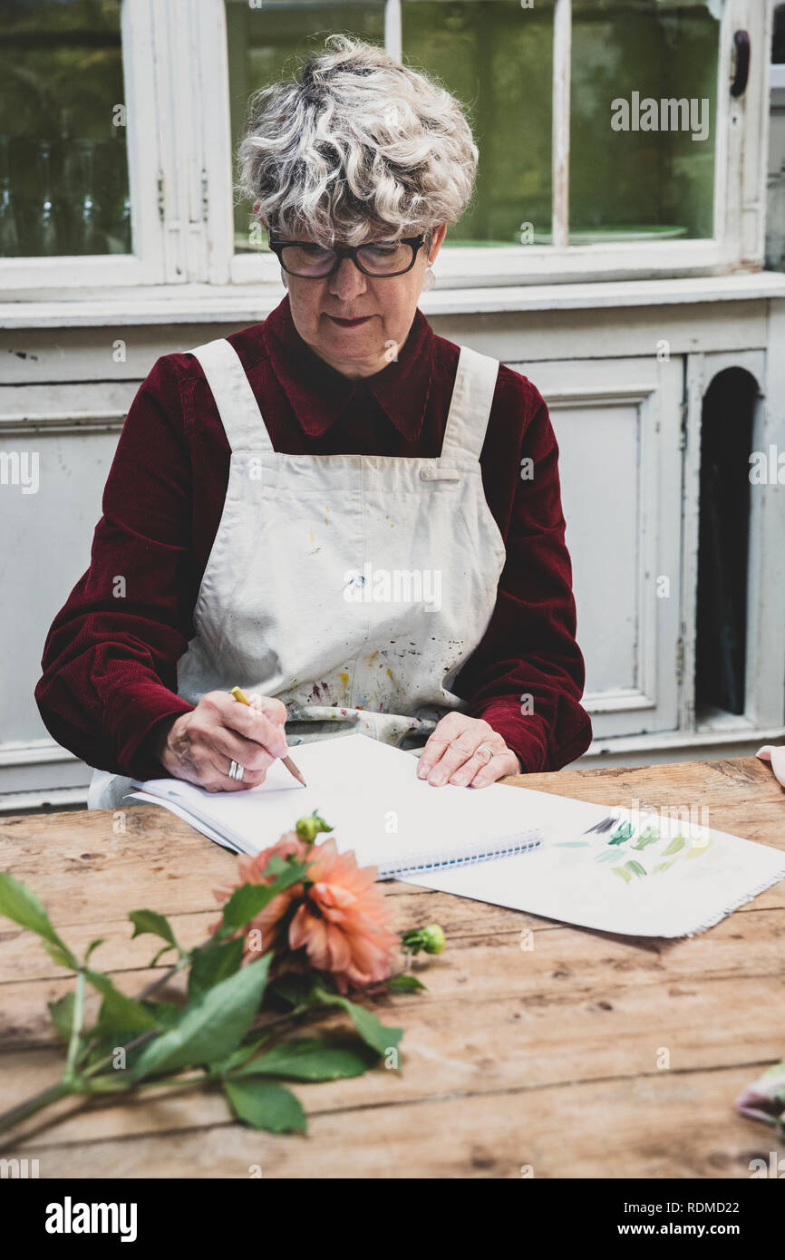 Senior woman wearing glasses, red dress and white apron sitting at ...