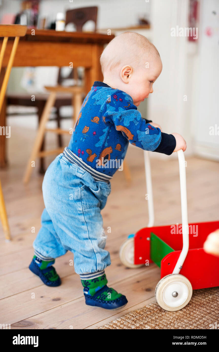 Baby boy pushing wooden cart Stock Photo - Alamy