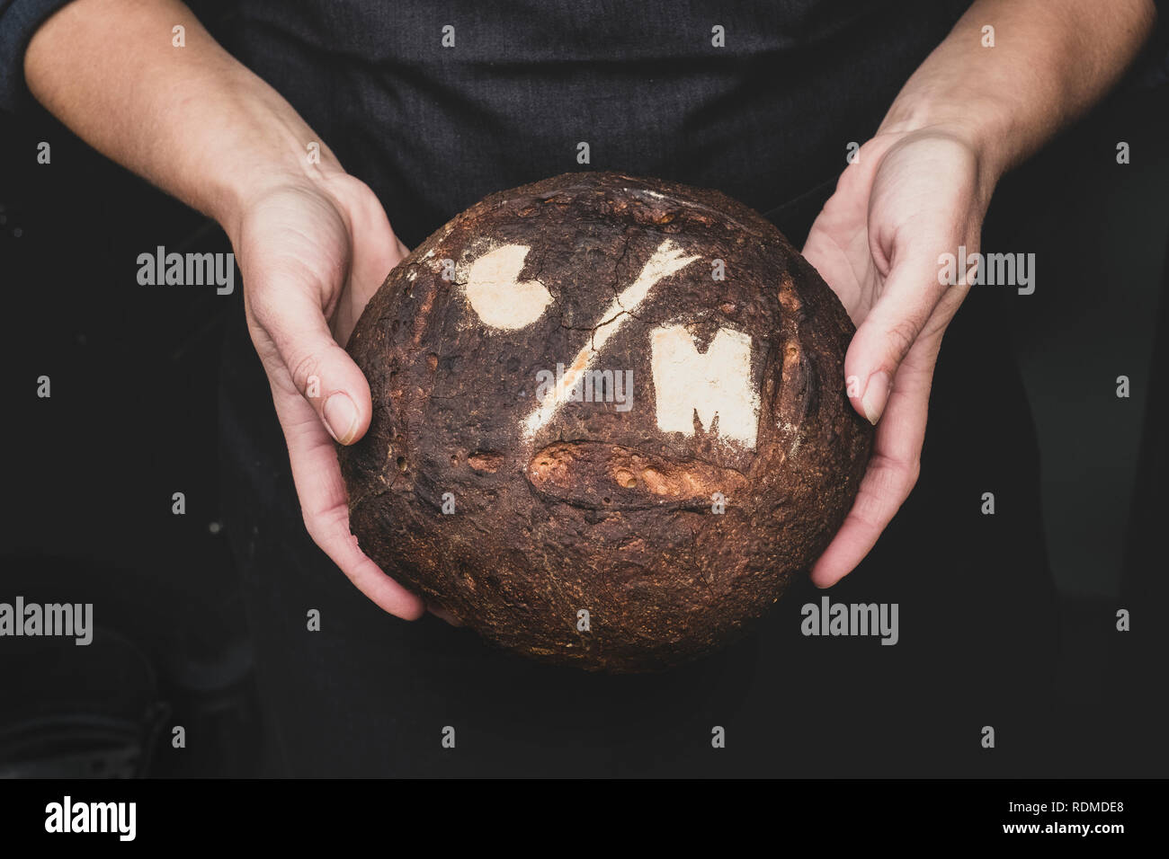 High angle close up of human hands holding freshly baked loaf of bread ...