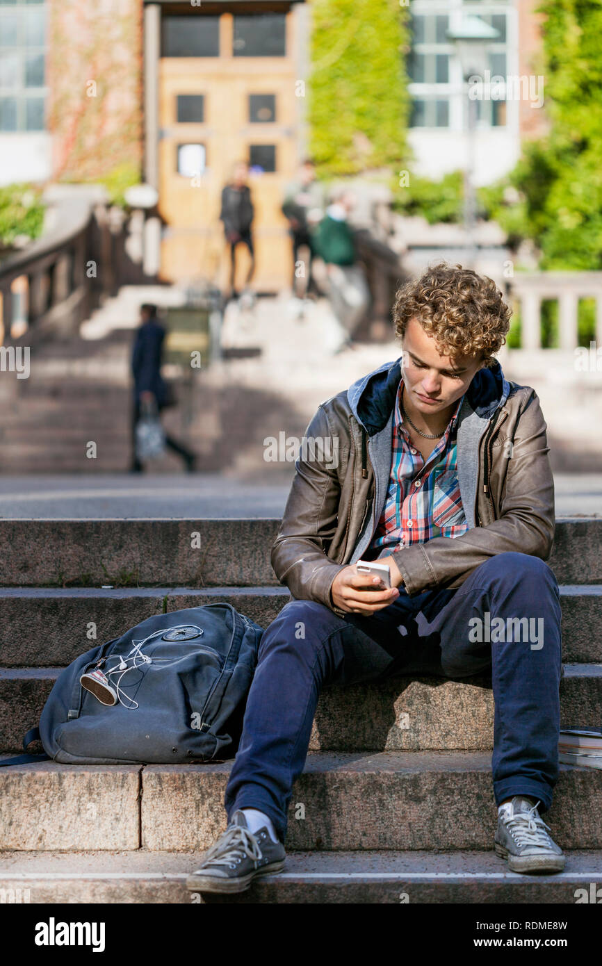 Young man sitting at a doorstep Stock Photo - Alamy