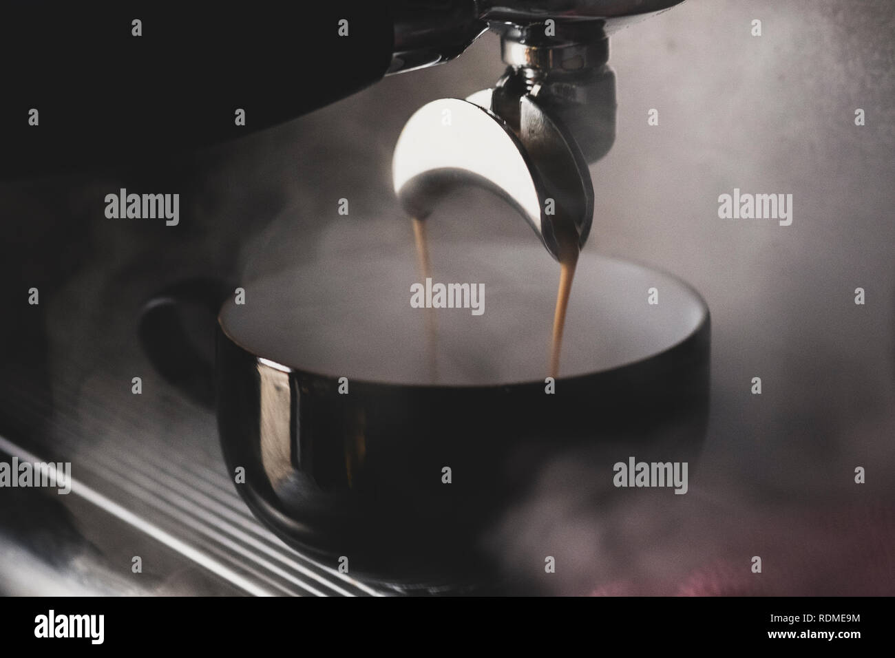 Close up of black mug on espresso machine, hot coffee pouring from ...