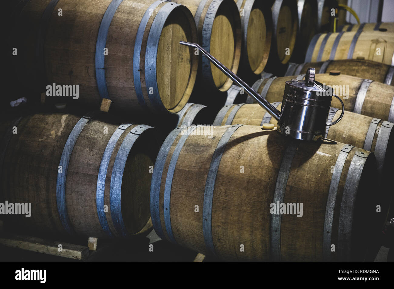 Stainless steel can on top of oak wood wine barrels in a cellar during ...