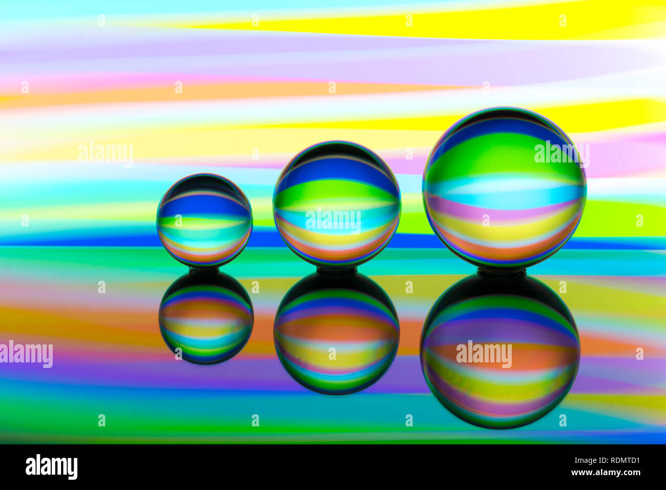 A row of three glass / crystal / sphere / lens balls with multicolored ...