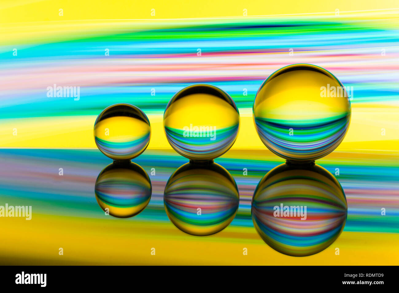 A row of three glass / crystal / sphere / lens balls with multicolored ...