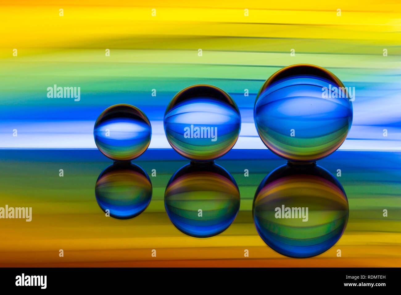 A row of three glass / crystal / sphere / lens balls with multicolored ...