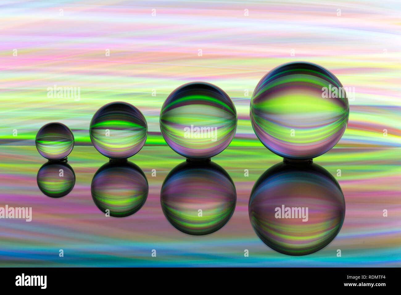 A row of four glass / crystal / sphere / lens balls with multicolored ...