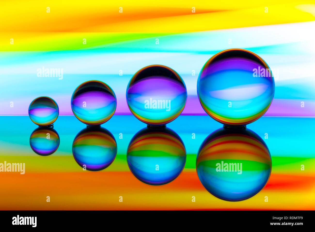A row of four glass / crystal / sphere / lens balls with multicolored ...