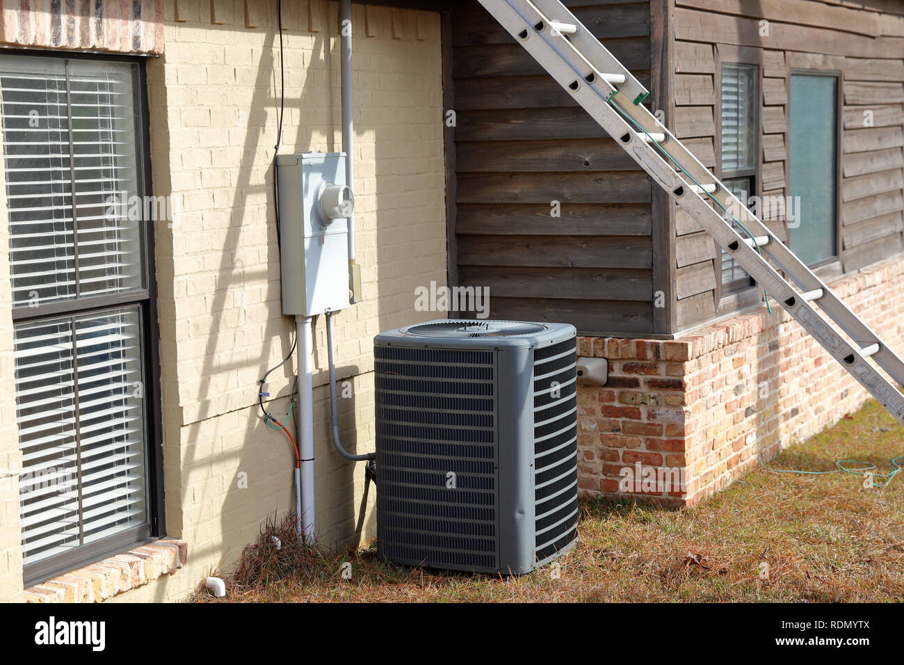 Gray Air Conditioner condenser compressor unit next to painted brick ...