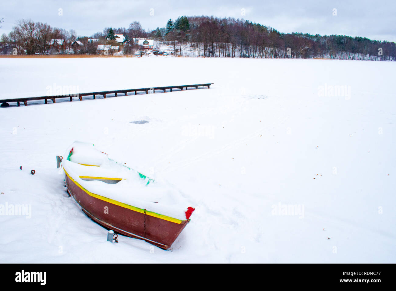 Wooden boat on a frozen lake with snow and pier Stock Photo - Alamy