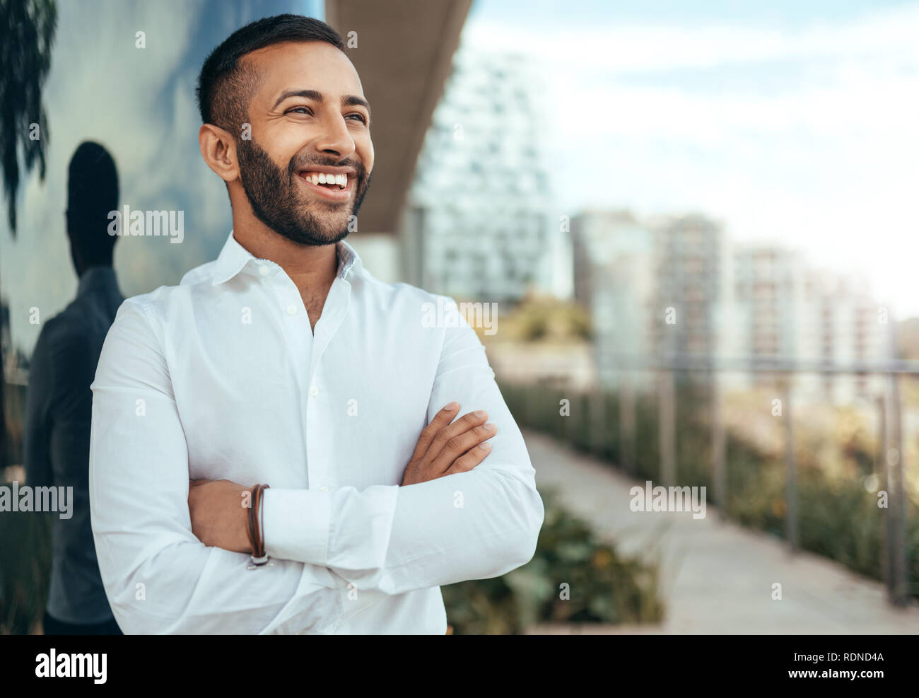 Portrait of a young confident smiling indian man with his arms crossed ...