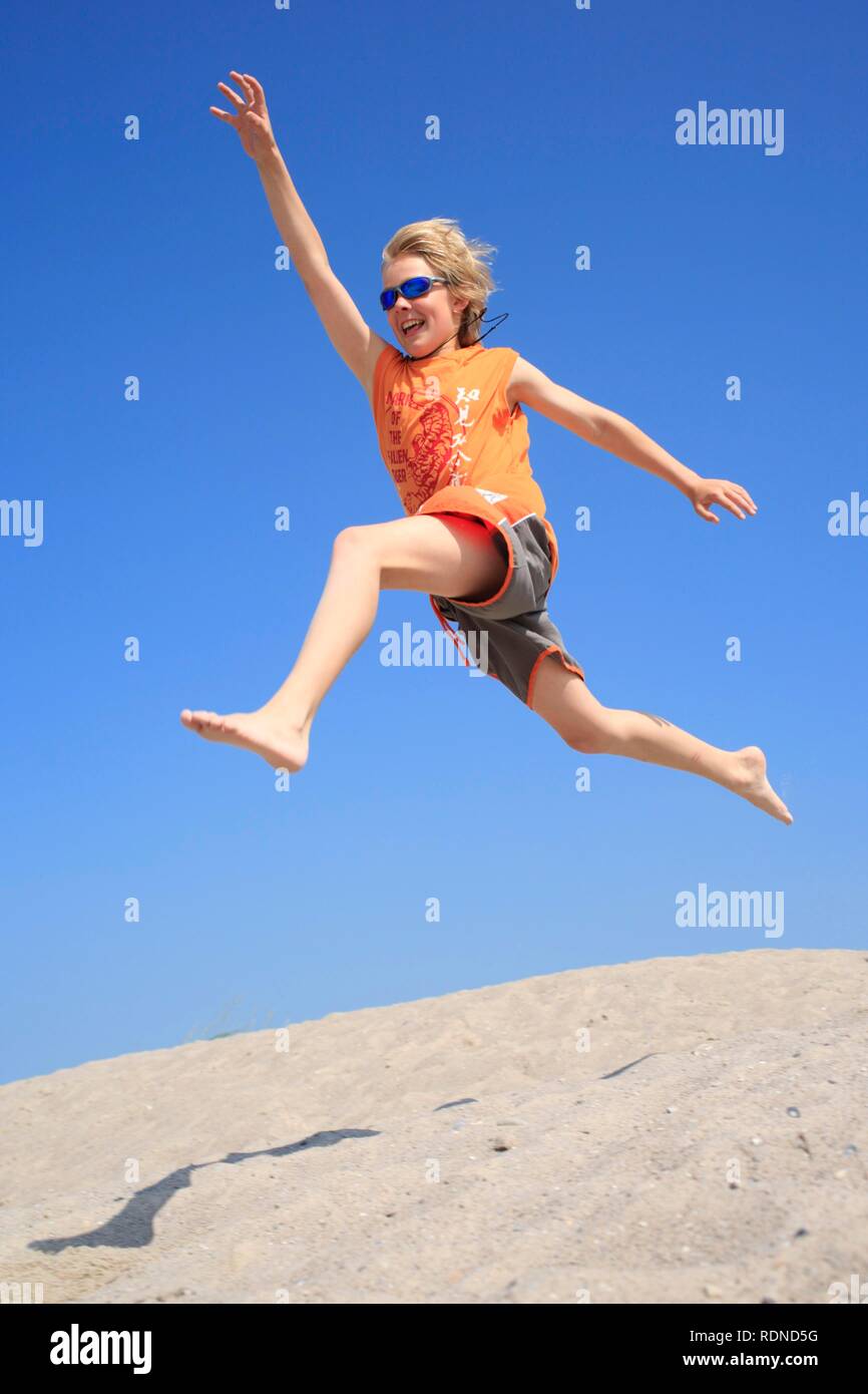 Boy jumping playfully from a dune Stock Photo - Alamy