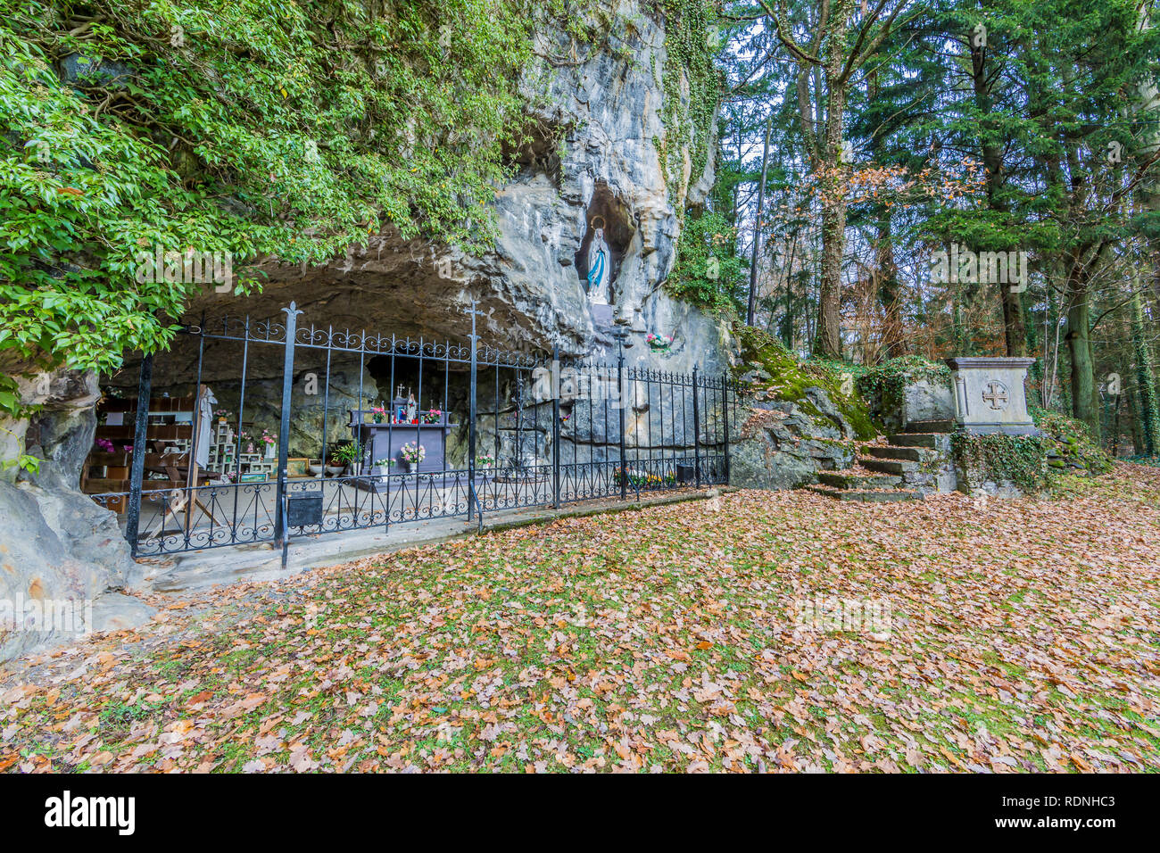 replica of the Virgin of Lourdes in a natural grotto with a metal fence ...